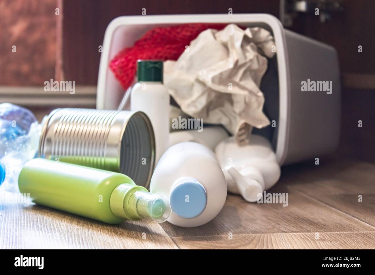 A plastic trash can with garbage lies on the floor near the kitchen ...