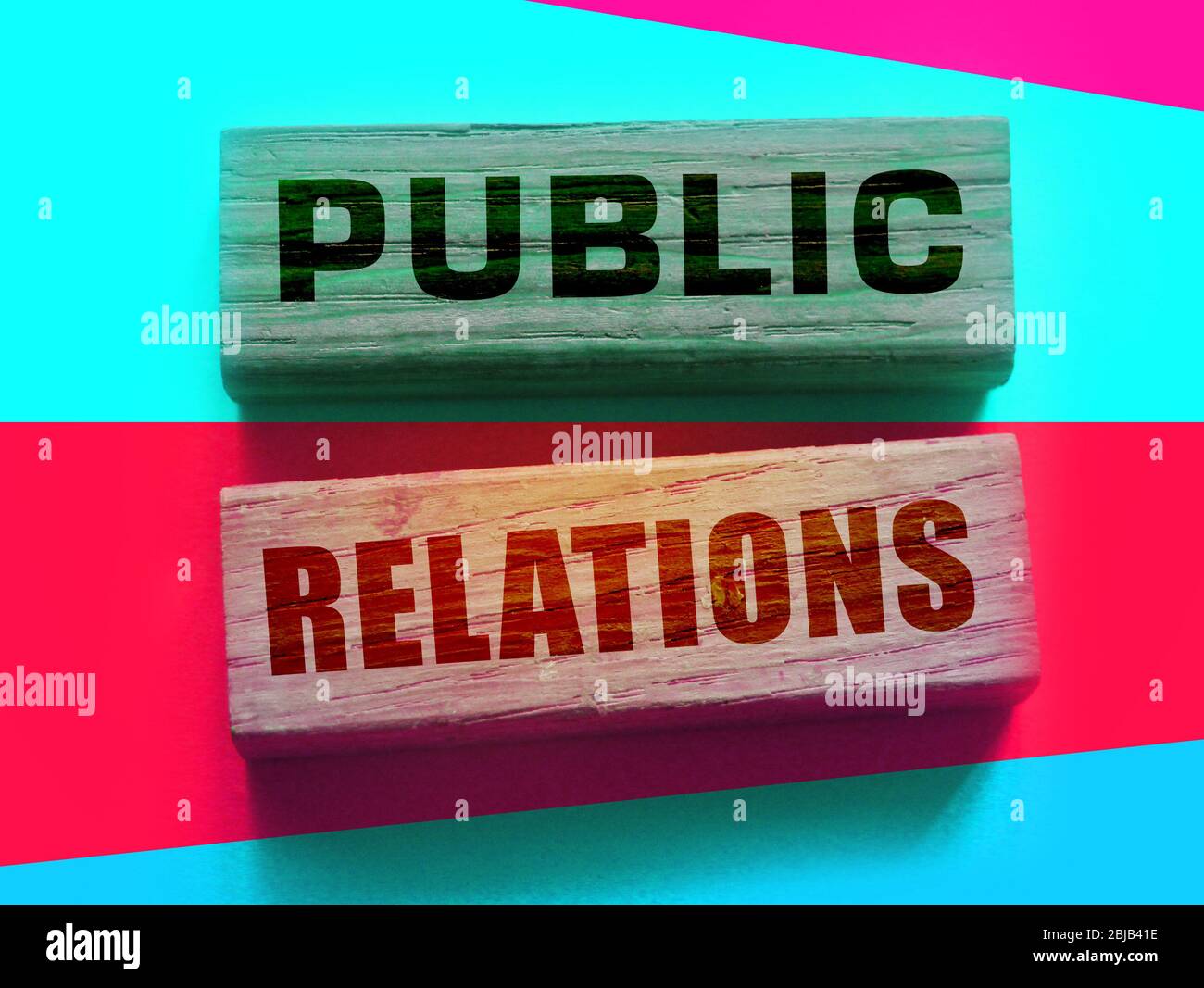 Public relation written in wooden blocks on a fluorescent red and cyan ...