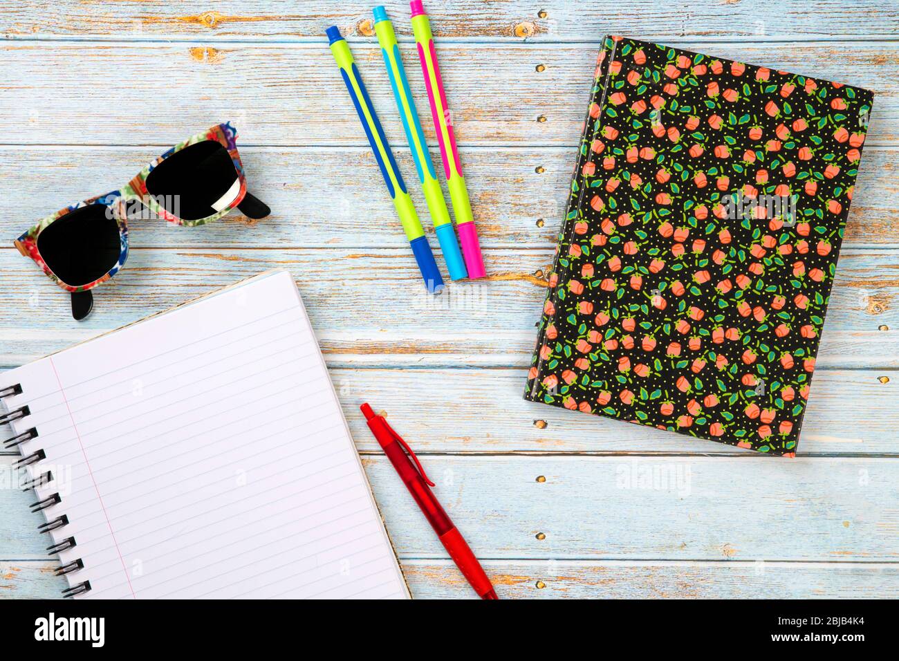 Top view of a wooden office desktop with sunglasses, markers, pen and a ...