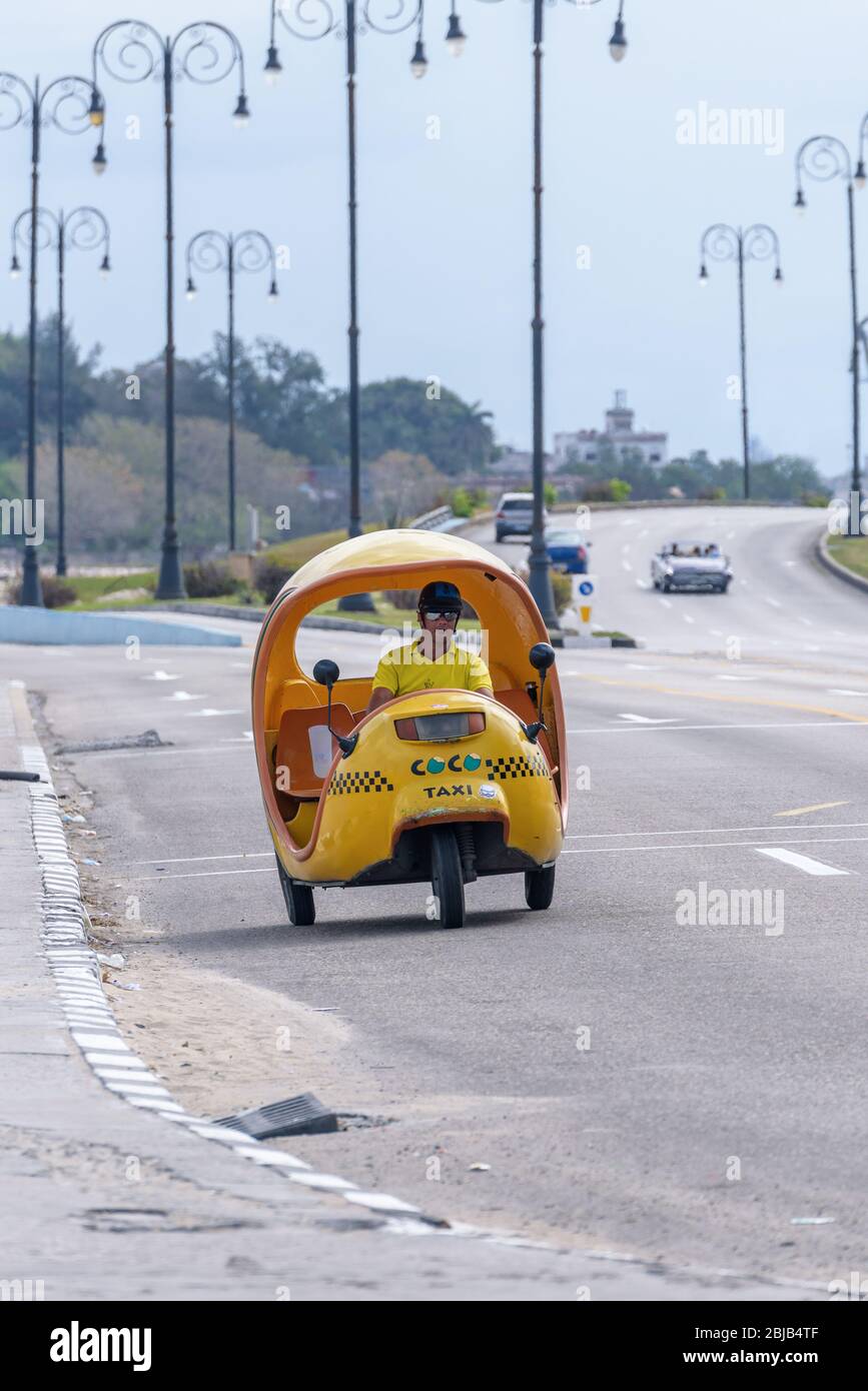 Old Havana, Cuba. Typical Coco Taxi passing by Malecon, Havana's famous ...