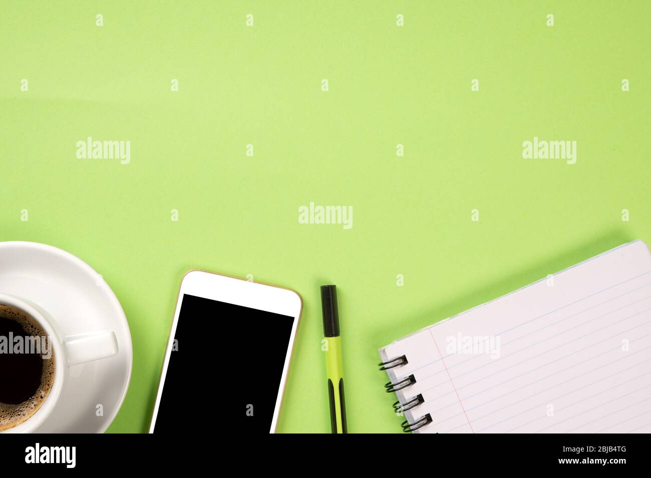 Top view from a light green color desk with stationery supplies, mobile ...