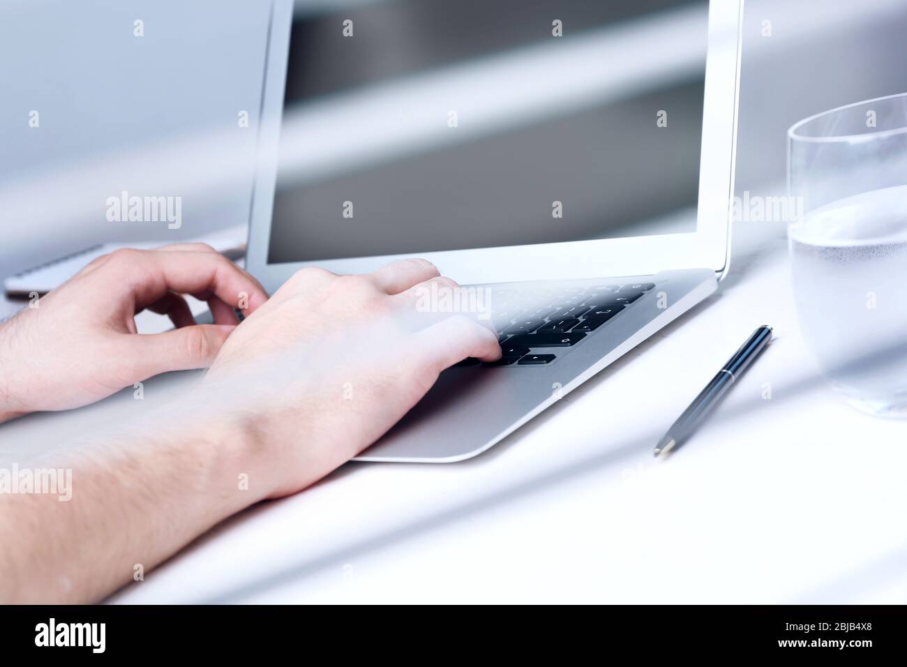 Man working on computer at wooden desk Stock Photo - Alamy