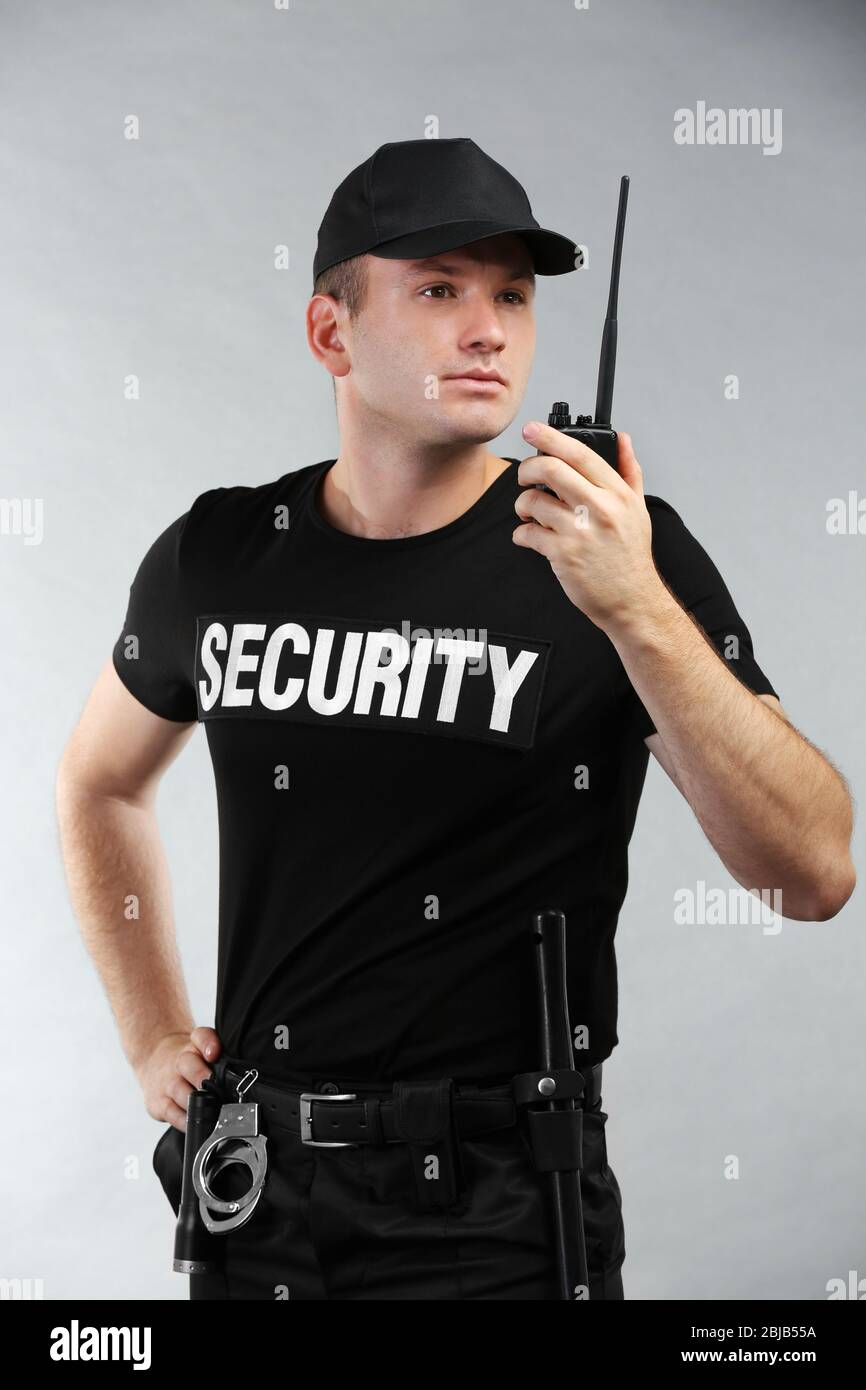 Male security guard on grey background Stock Photo - Alamy
