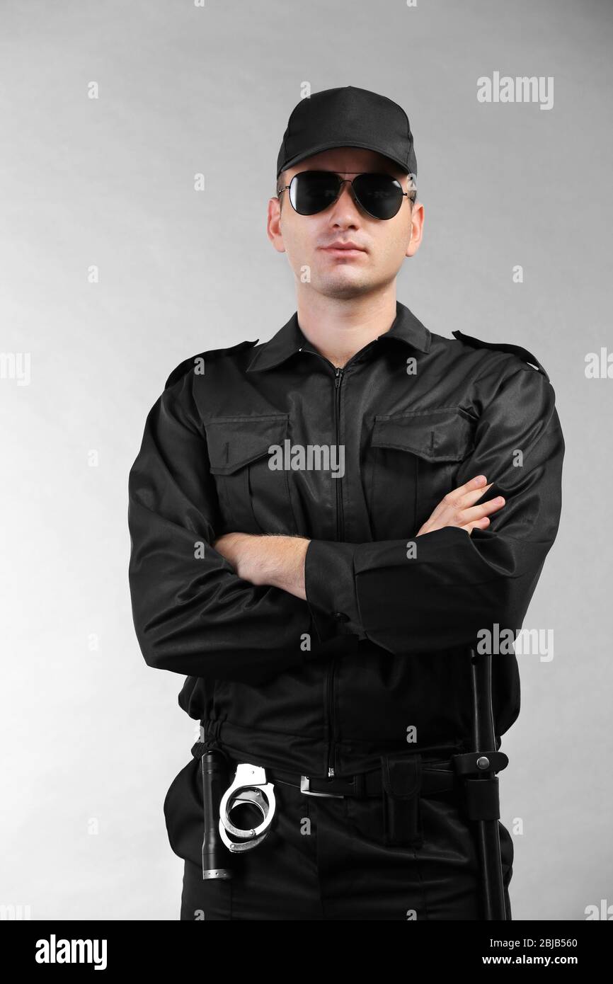 Male security guard on grey background Stock Photo - Alamy