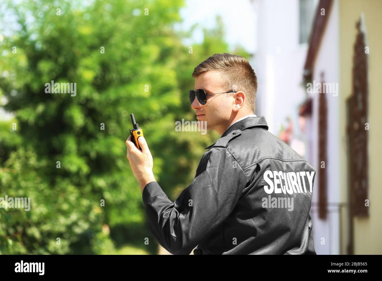 Male security guard with portable radio outdoors Stock Photo - Alamy