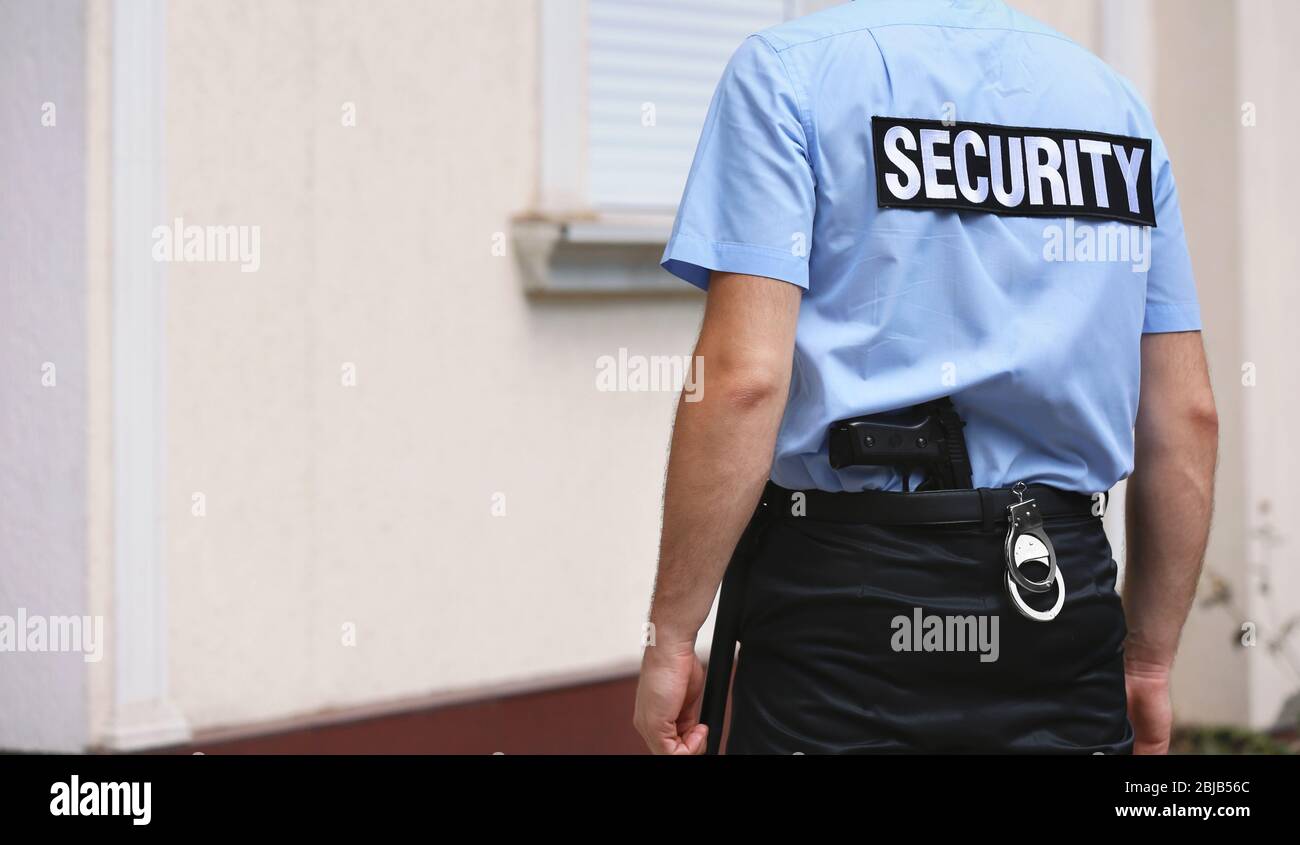 Male security guard standing back outdoors Stock Photo - Alamy