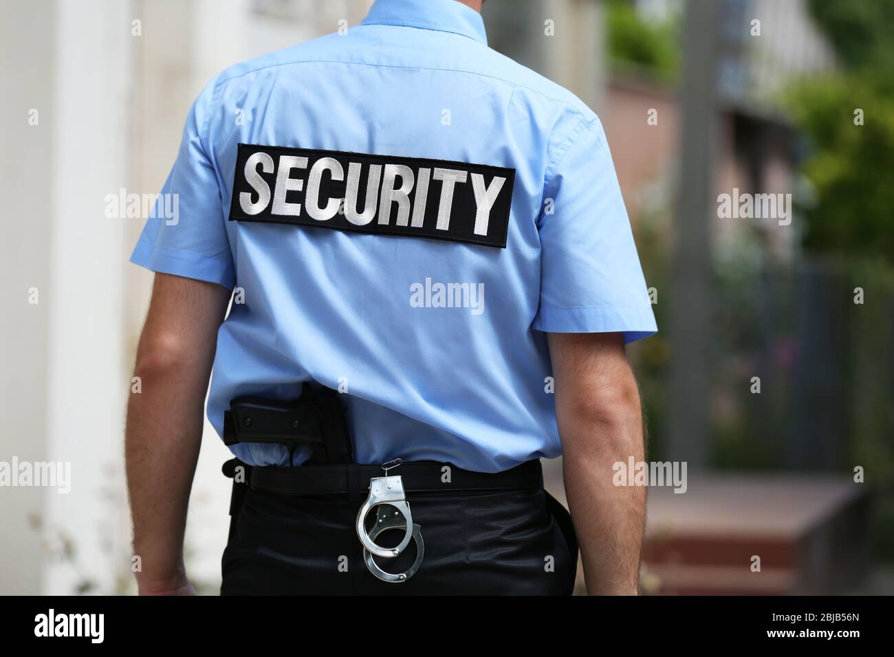 Male security guard standing back outdoors Stock Photo - Alamy