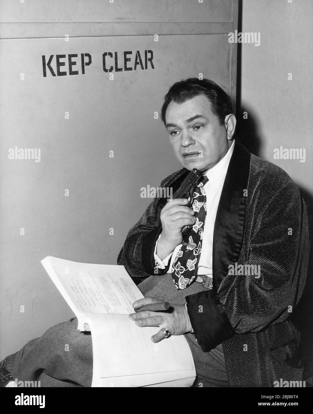 EDWARD G. ROBINSON reading his script and holding gun on set candid ...