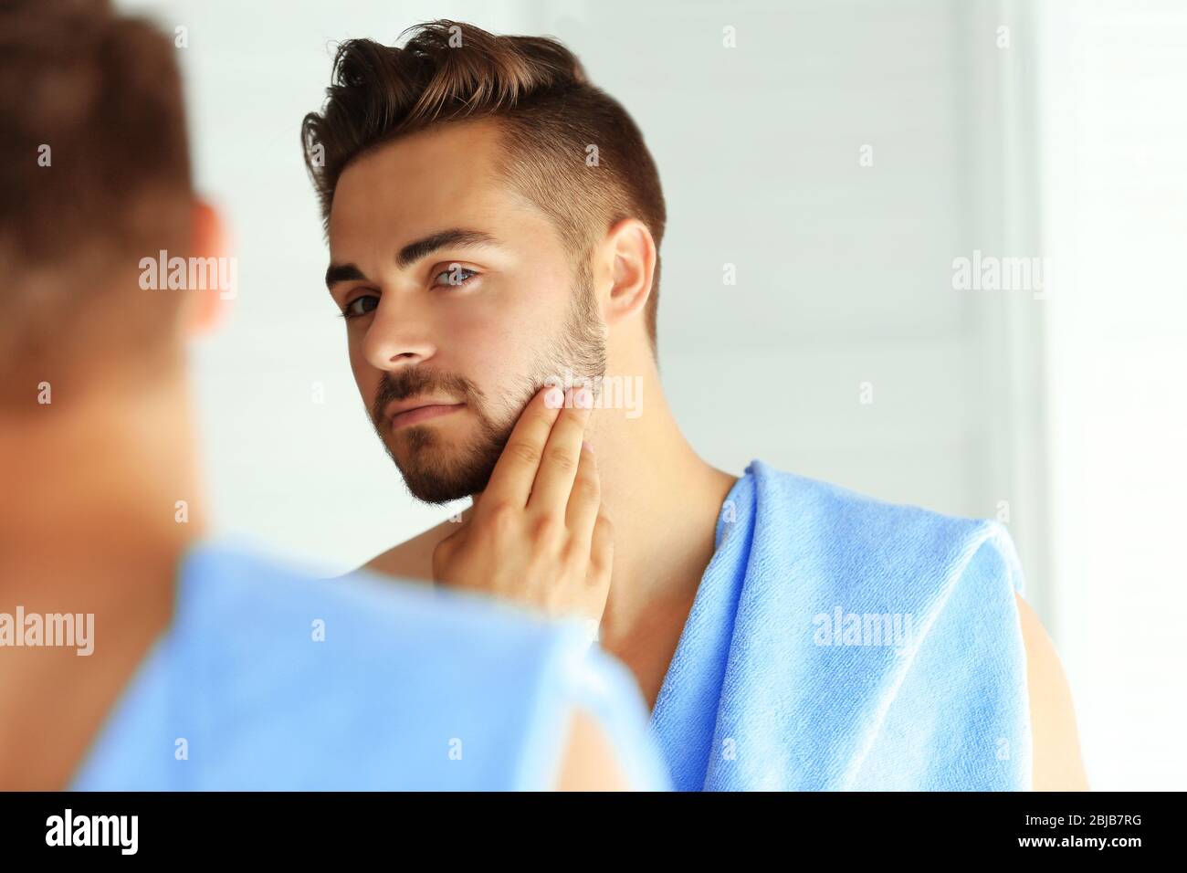 Handsome unshaven man looking in mirror Stock Photo - Alamy
