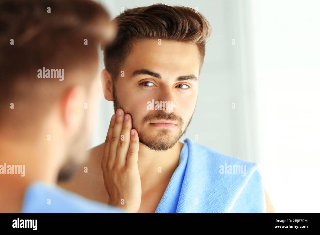 Handsome unshaven man looking in mirror Stock Photo - Alamy