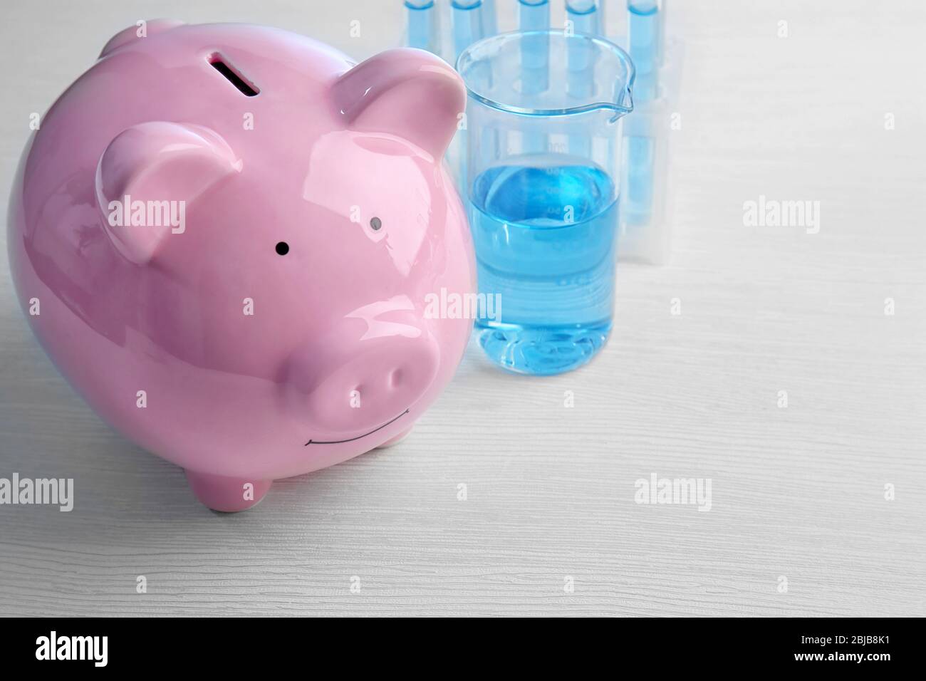 Pig money box and water in tubes on table. Saving water concept Stock ...