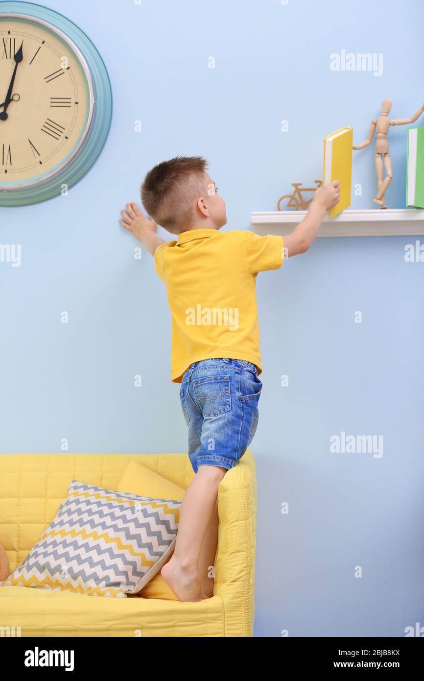 Cute boy taking book from shelf Stock Photo - Alamy