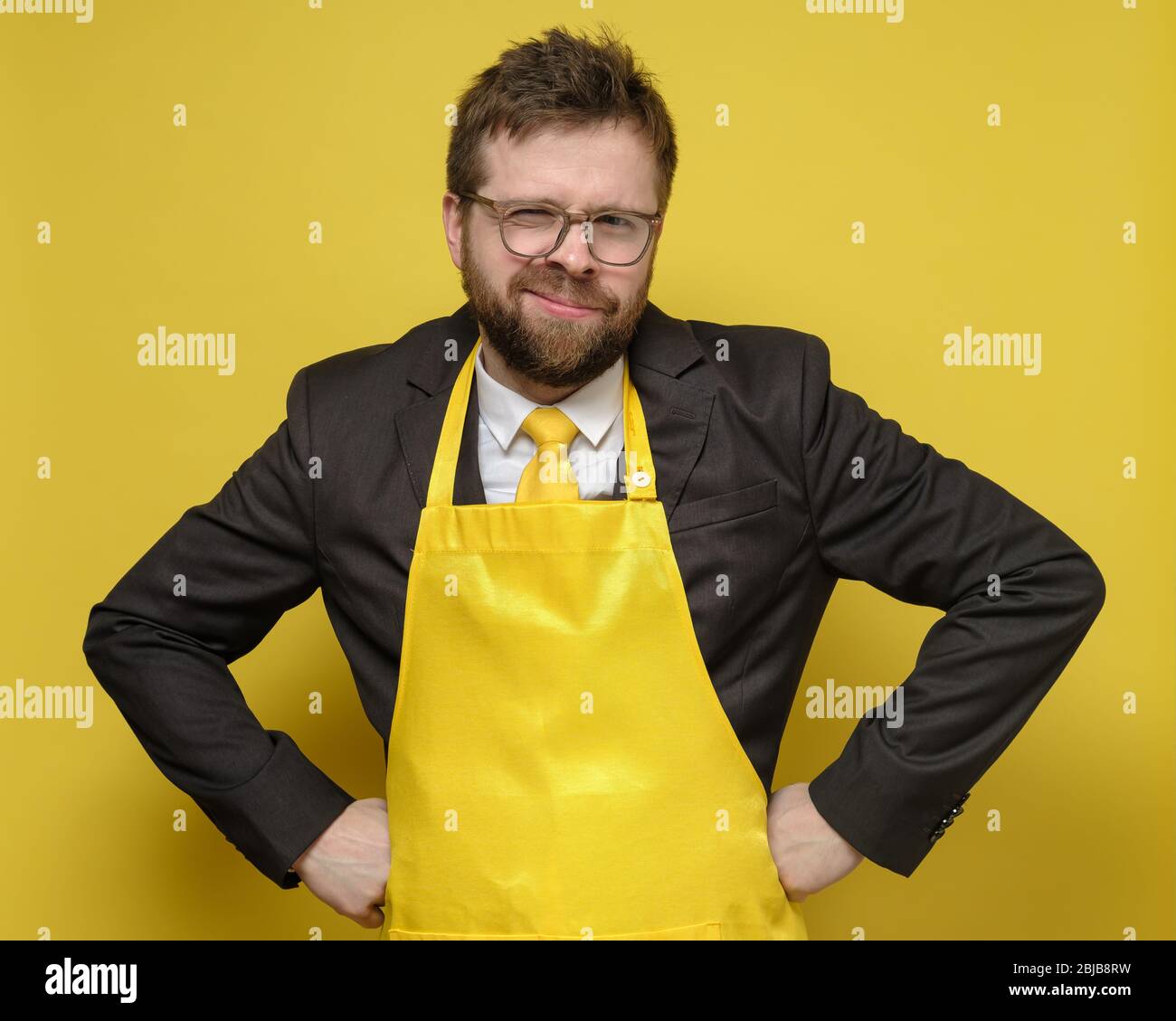 Strange man in a black suit and yellow apron is standing and holding ...