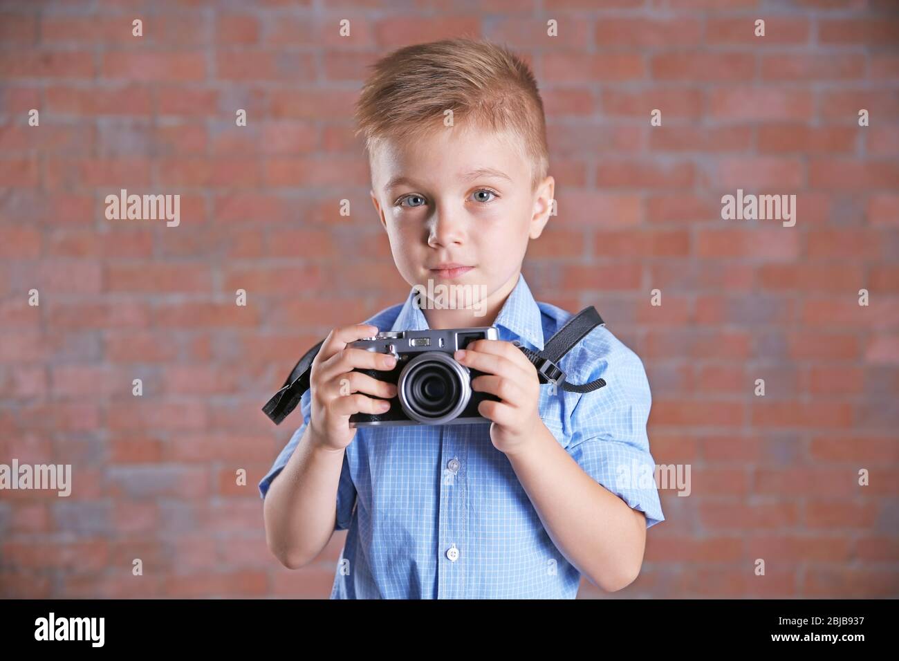 Little boy with vintage camera on brick wall background Stock Photo - Alamy
