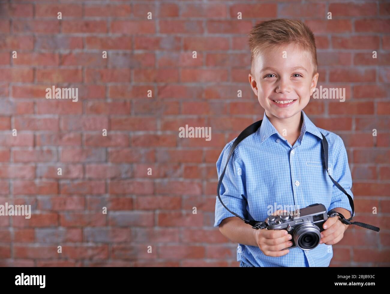 Little boy with vintage camera on brick wall background Stock Photo - Alamy