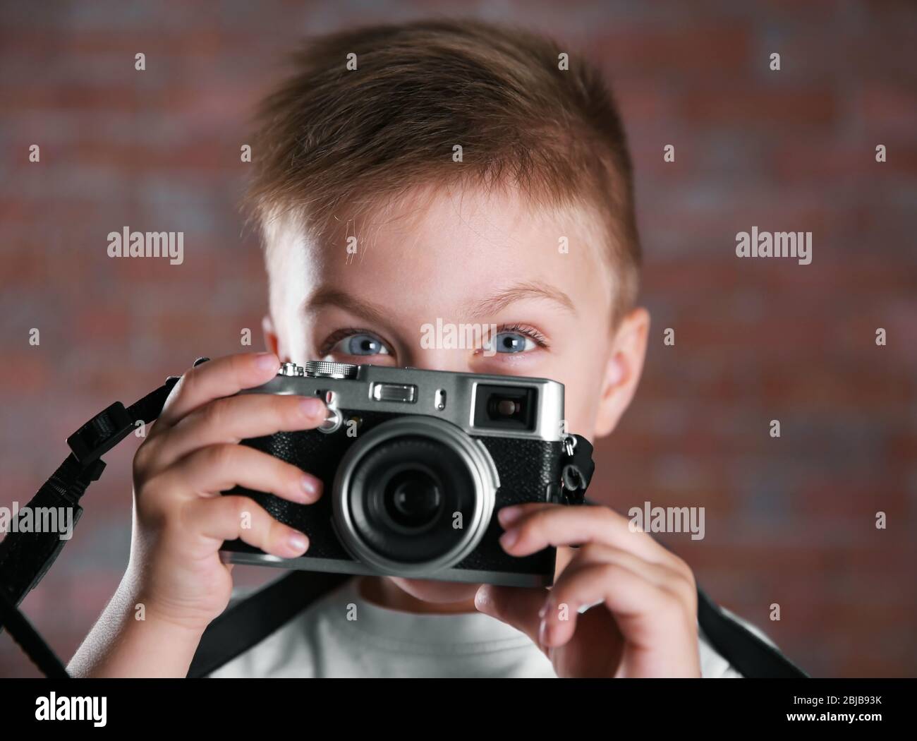 Little boy with vintage camera on brick wall background Stock Photo - Alamy