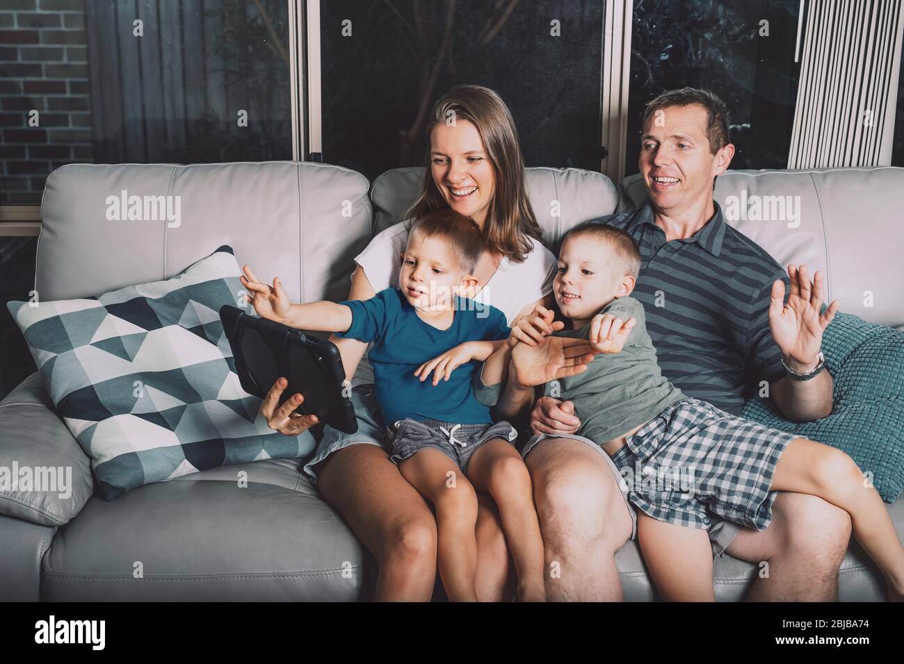 Family of parents and two little sons communicating with relatives via ...