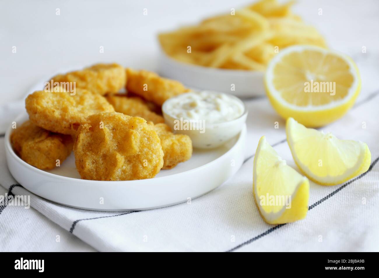 Tasty nuggets with sauce in plate and lemon on napkin Stock Photo - Alamy