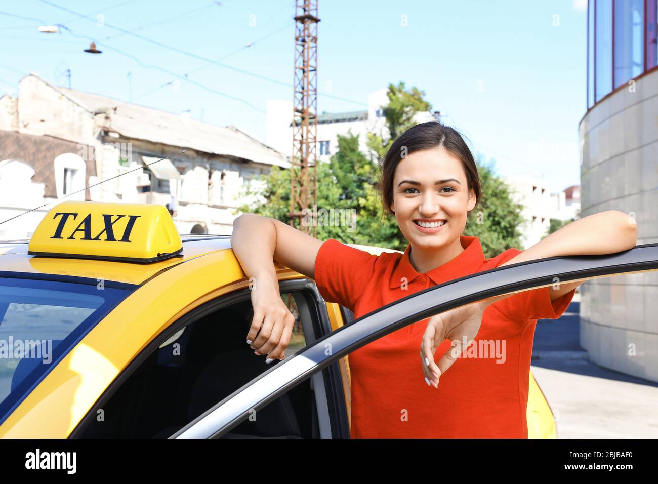 Beautiful female taxi driver standing near car Stock Photo - Alamy