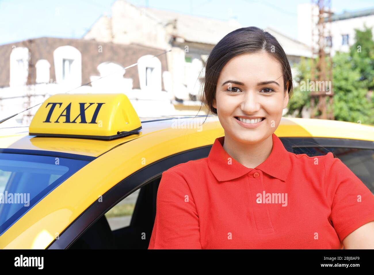 Beautiful female taxi driver standing near car Stock Photo - Alamy