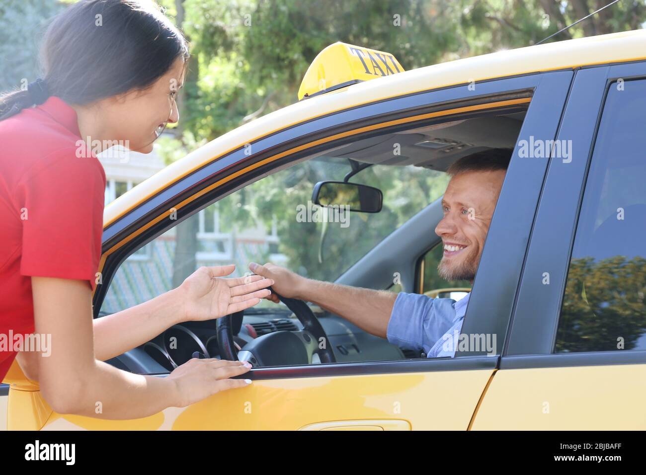 Beautiful woman talking with taxi driver through opened car window ...