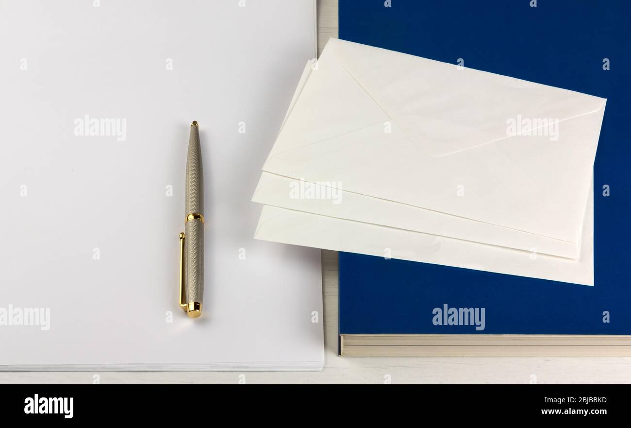 A book, three envelopes, an elegant pen and a small pile of white paper ...