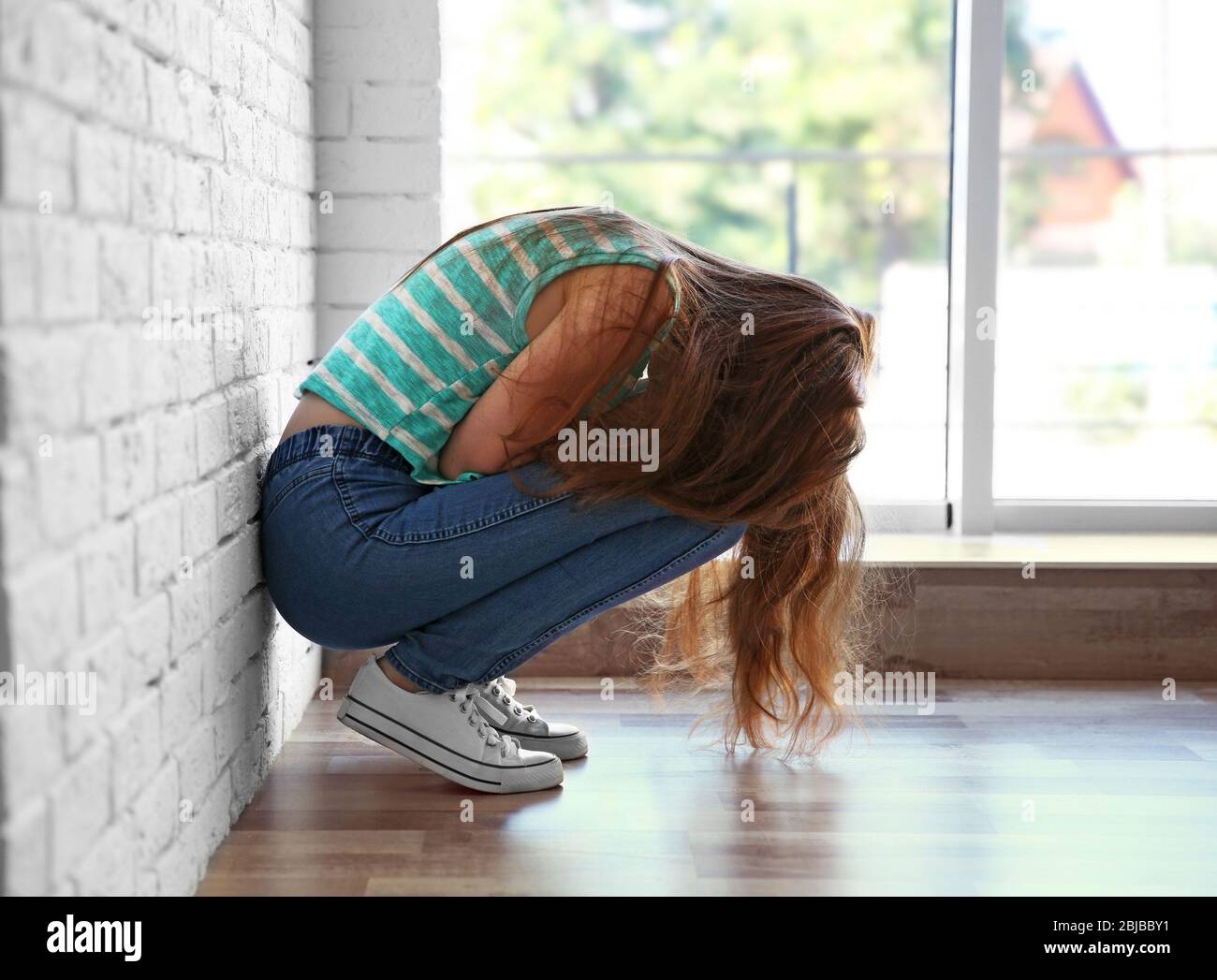 Sad teenage girl sitting near window in a room Stock Photo - Alamy