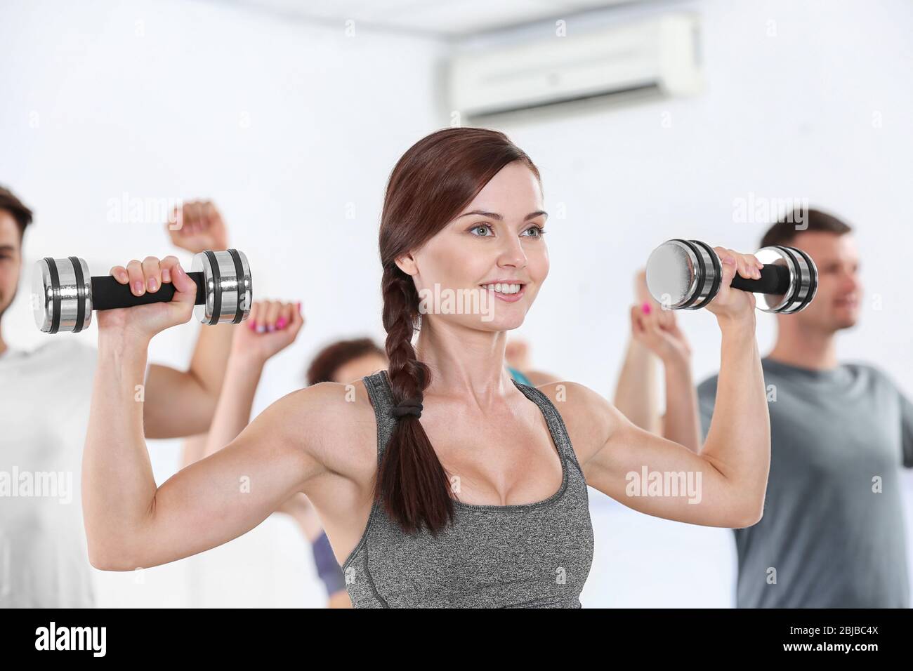 Group of people doing exercises with dumbbells in gym Stock Photo - Alamy