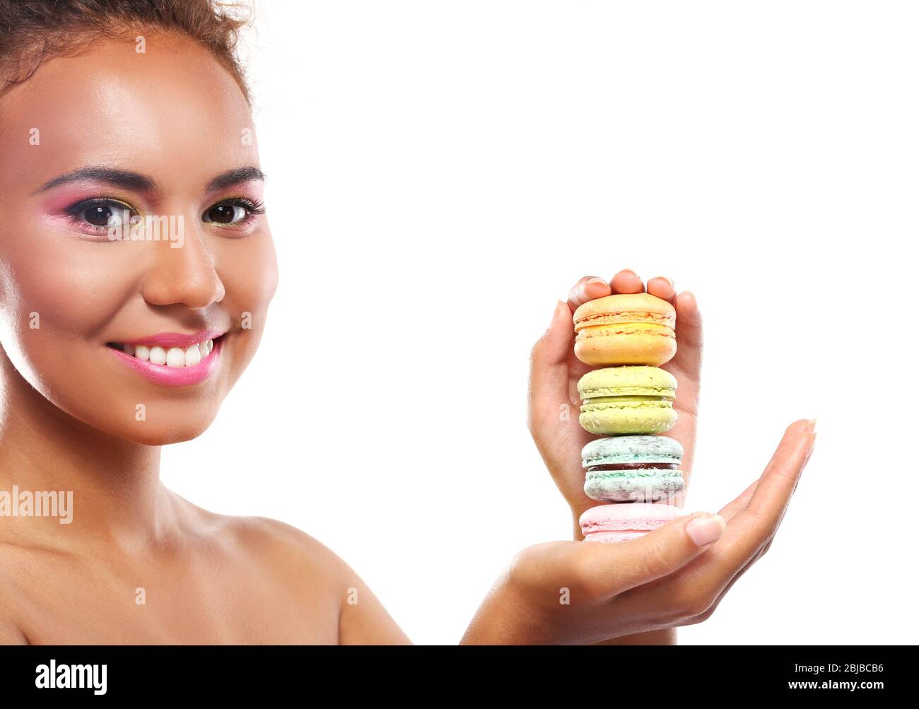 African-American young woman holding pile of macaroons on white ...