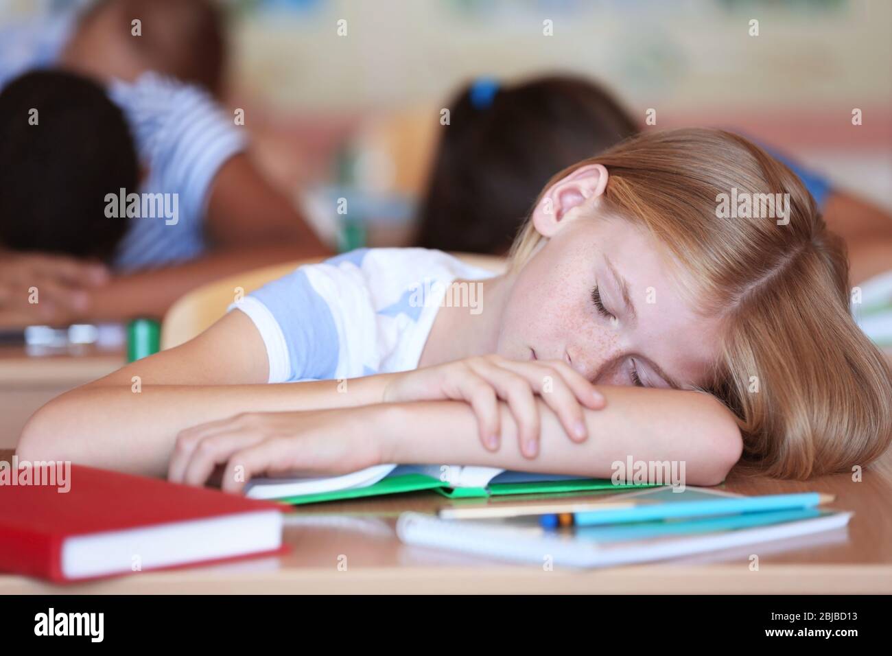 Tired schoolgirl in classroom on lesson Stock Photo - Alamy