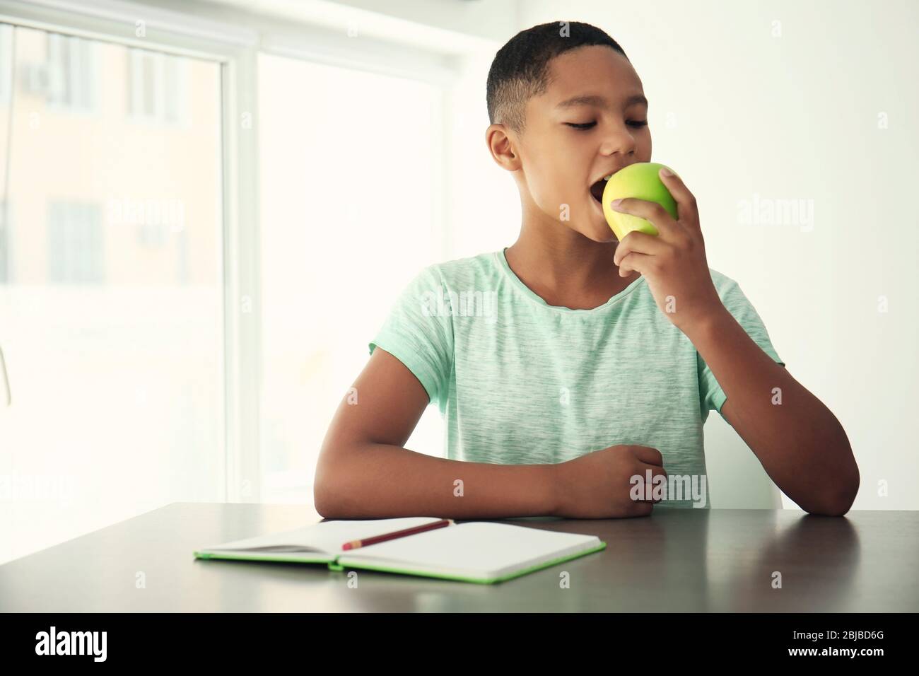 African American boy eating apple on light background Stock Photo - Alamy