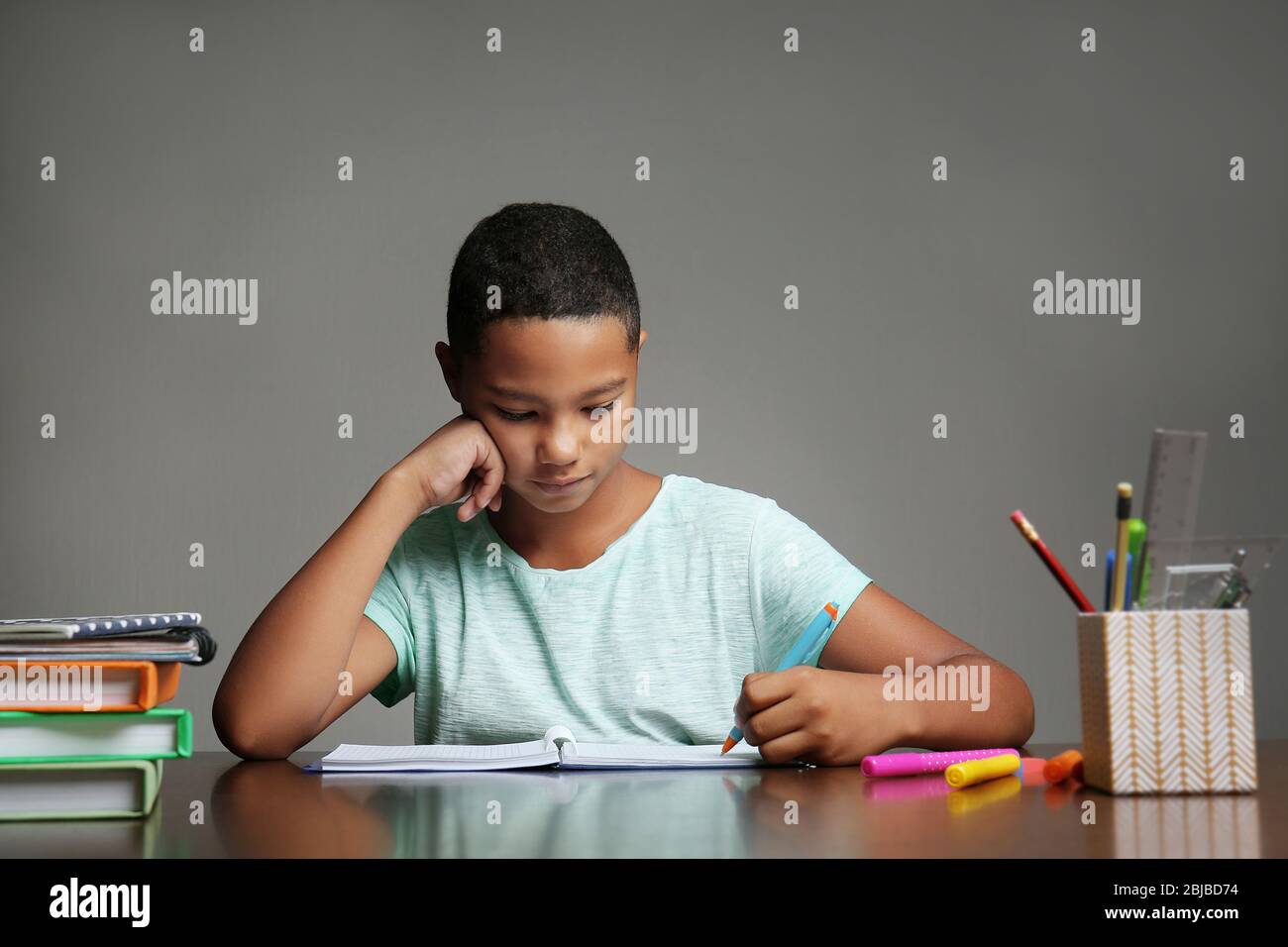 African American boy making homework on grey background Stock Photo - Alamy