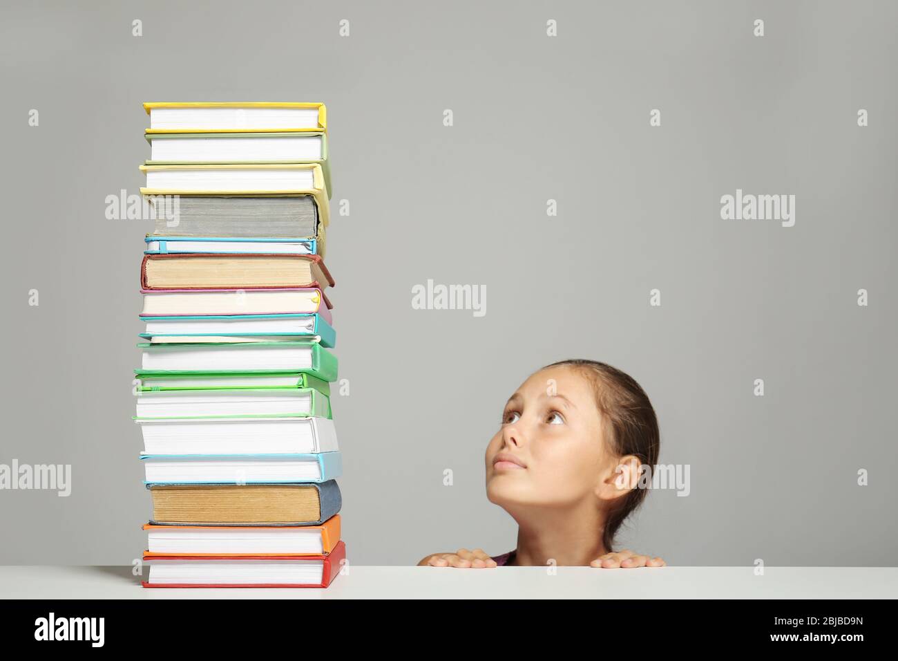Cute girl with books on grey background Stock Photo - Alamy