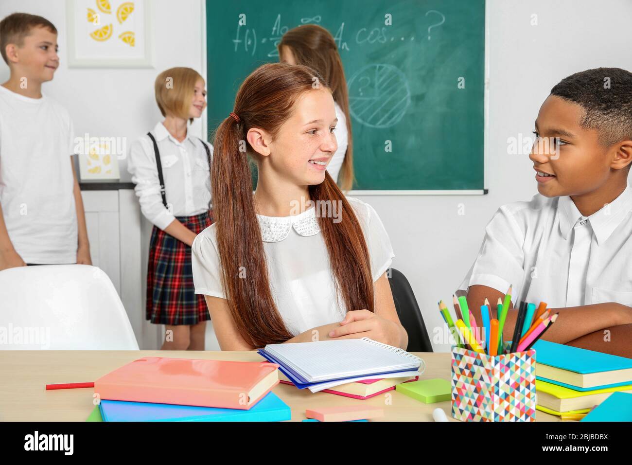 Schoolchildren sitting at table in classroom Stock Photo - Alamy