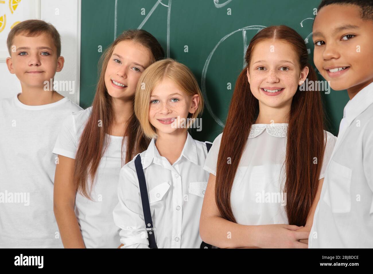Schoolchildren standing in classroom near blackboard Stock Photo - Alamy