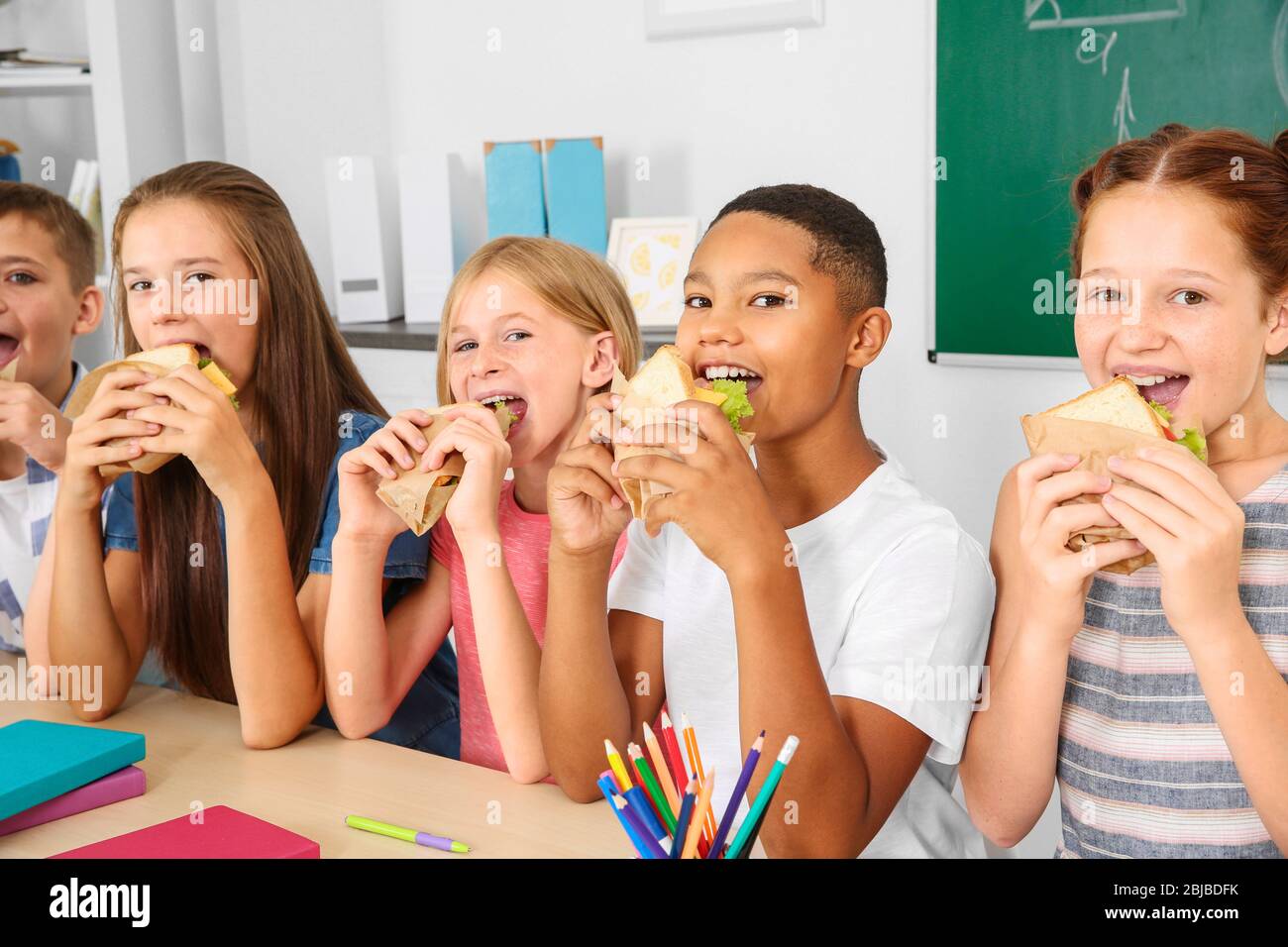 Schoolchildren having lunch in classroom Stock Photo - Alamy