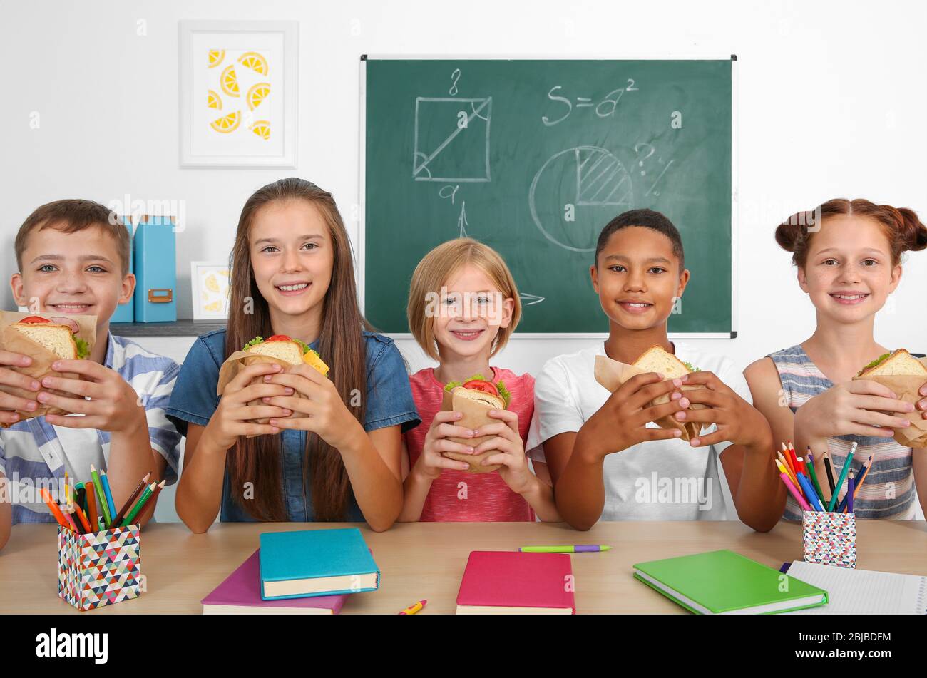 Schoolchildren having lunch in classroom Stock Photo - Alamy