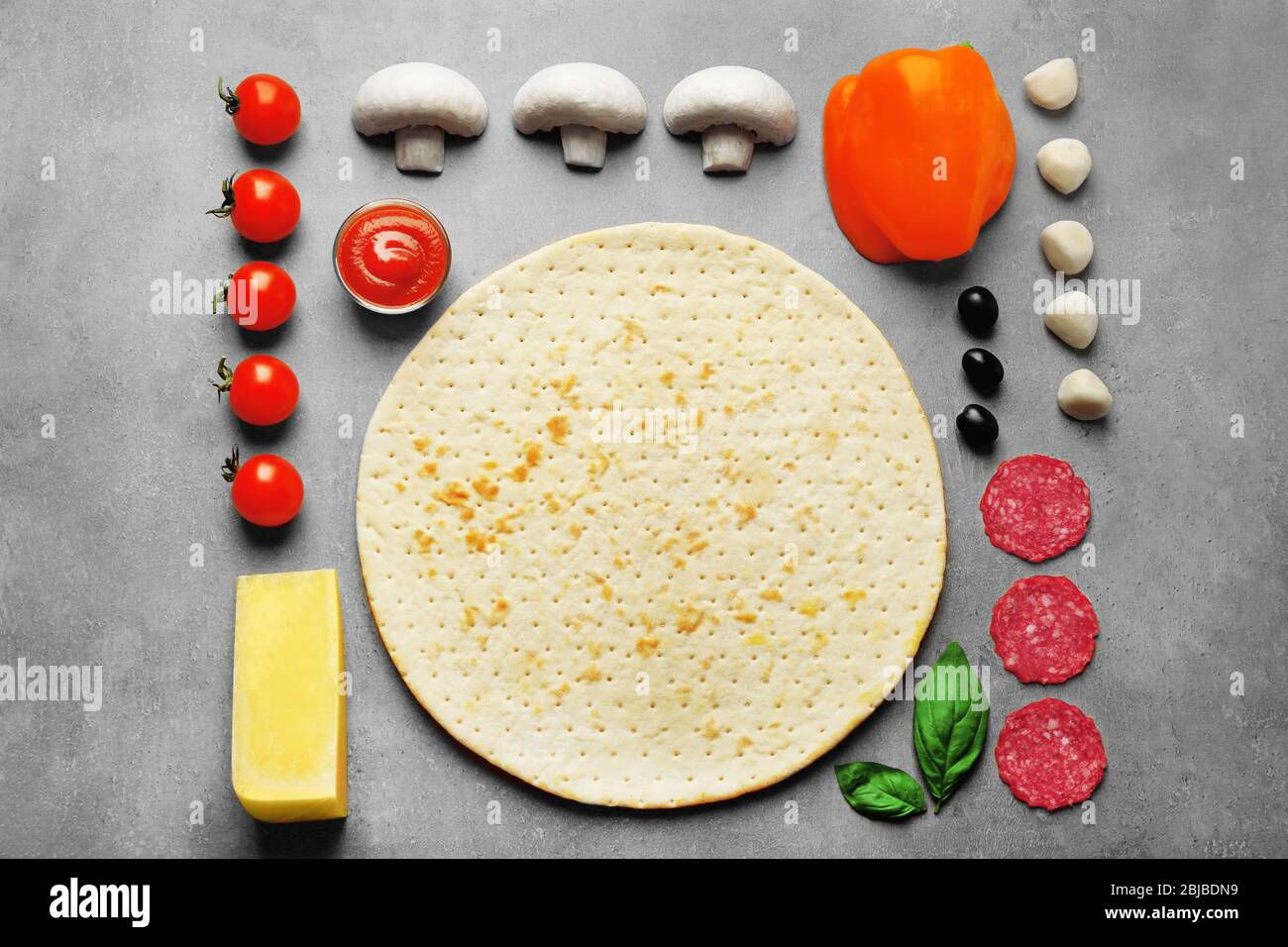 Raw pizza ingredients on the grey board with copy space on the center ...