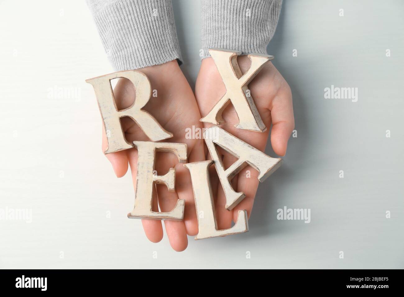 Word RELAX of wooden letters in female hands and on white background ...