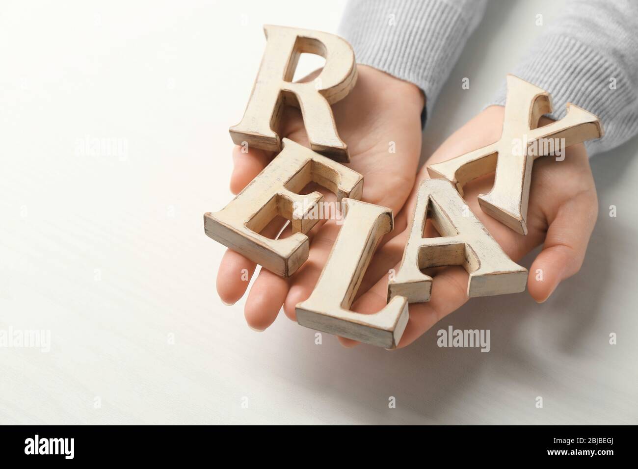 Word RELAX of wooden letters in female hands and on white background ...