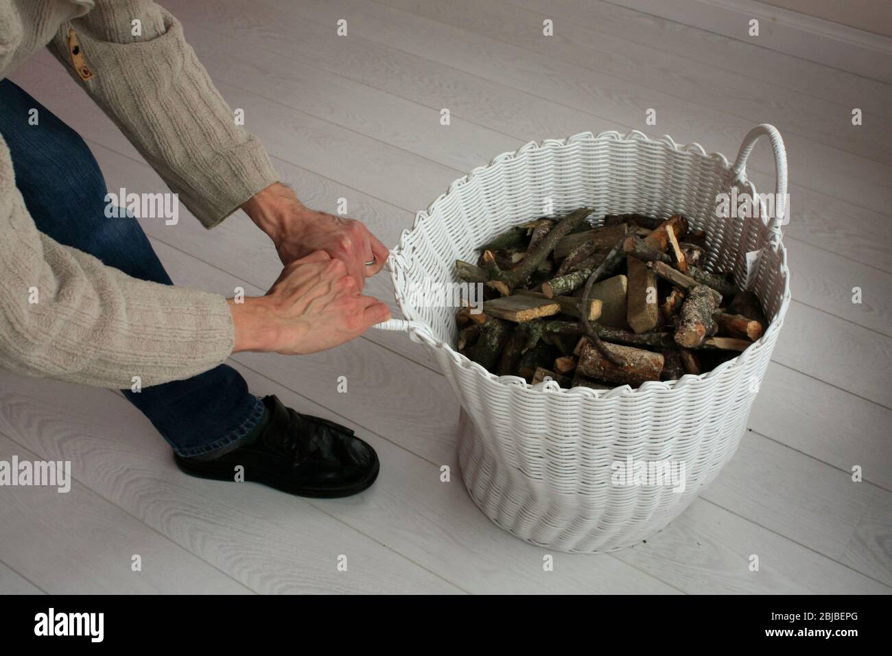 Male pulling basket of fire wood across floor Stock Photo - Alamy