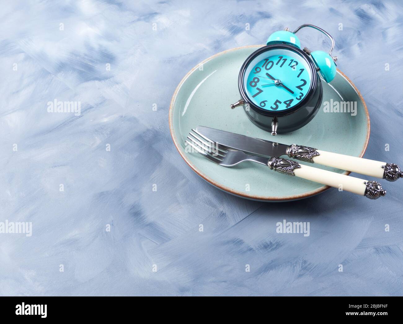 Intermittent fasting concept with blue alarm clock Stock Photo - Alamy