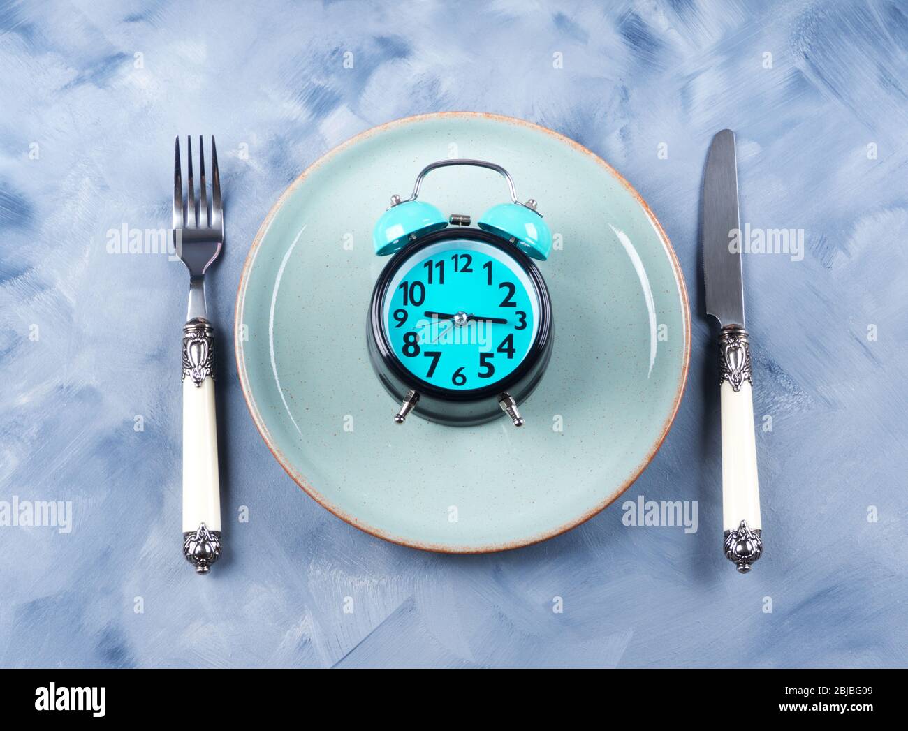 Intermittent fasting concept with blue alarm clock Stock Photo - Alamy