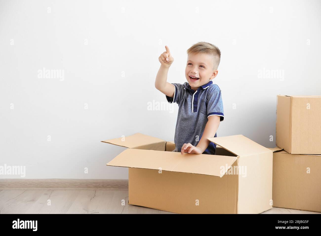 Little boy playing with cardboard boxes on white wall background Stock ...
