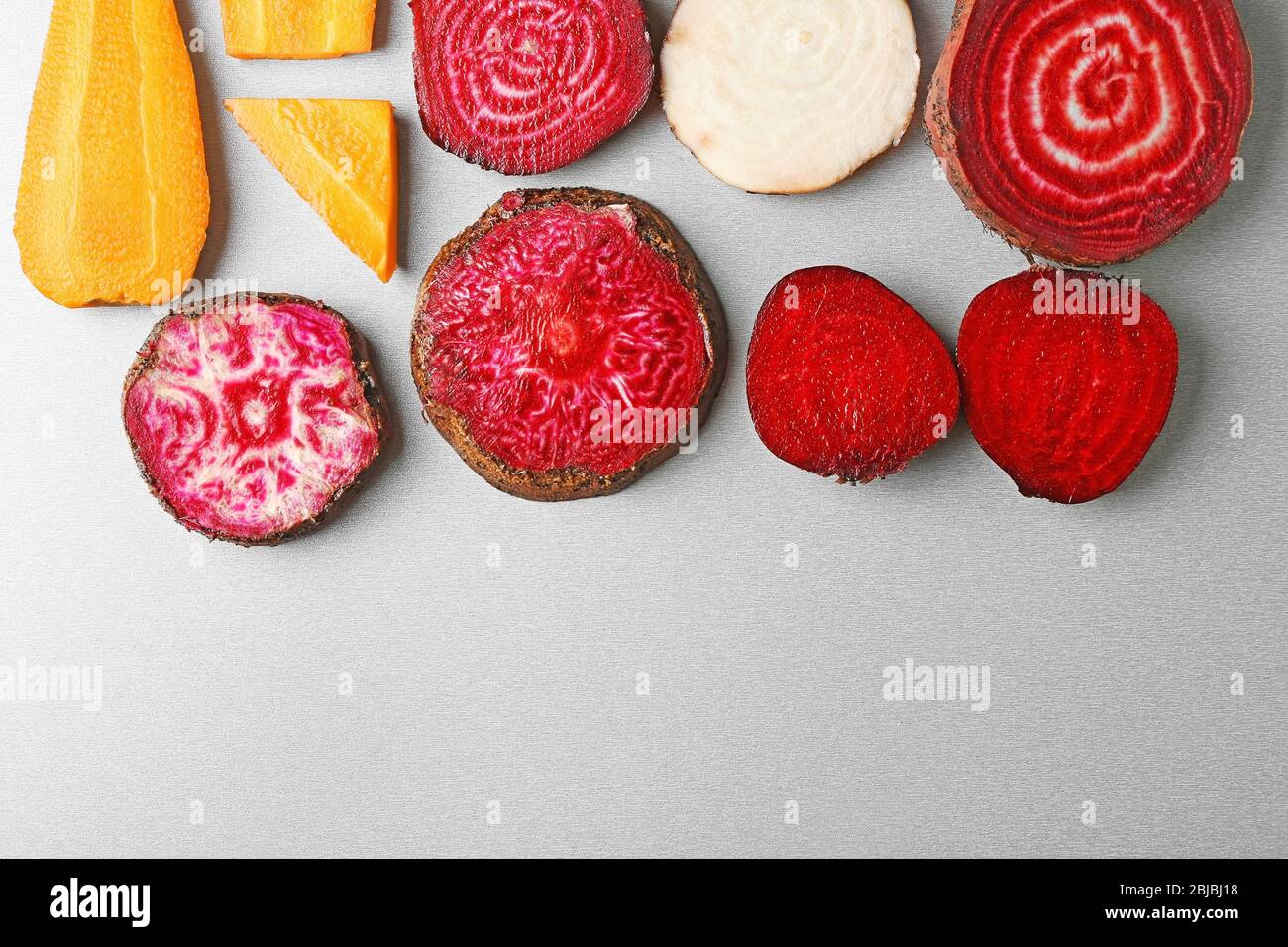 Fresh young sliced beets and carrots on grey background Stock Photo - Alamy