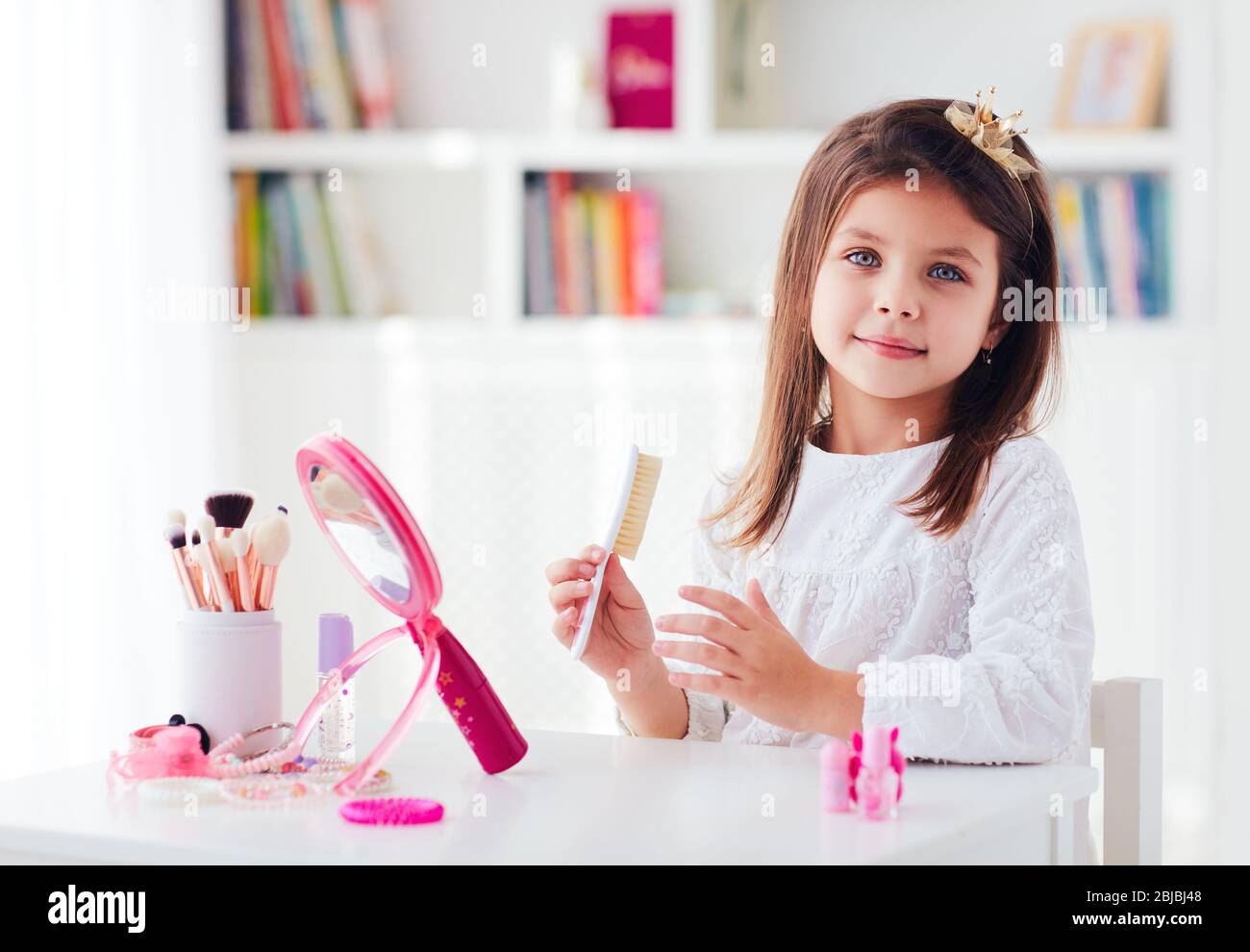 beautiful young girl, kid brushing the hair, applying makeup with toy ...