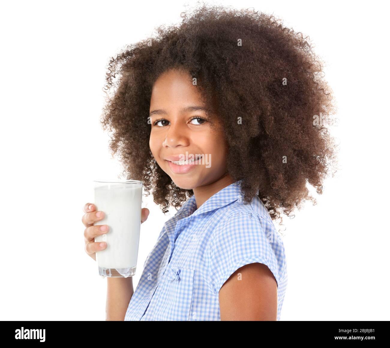 Cute curly African-American girl drinking milk on a white background ...