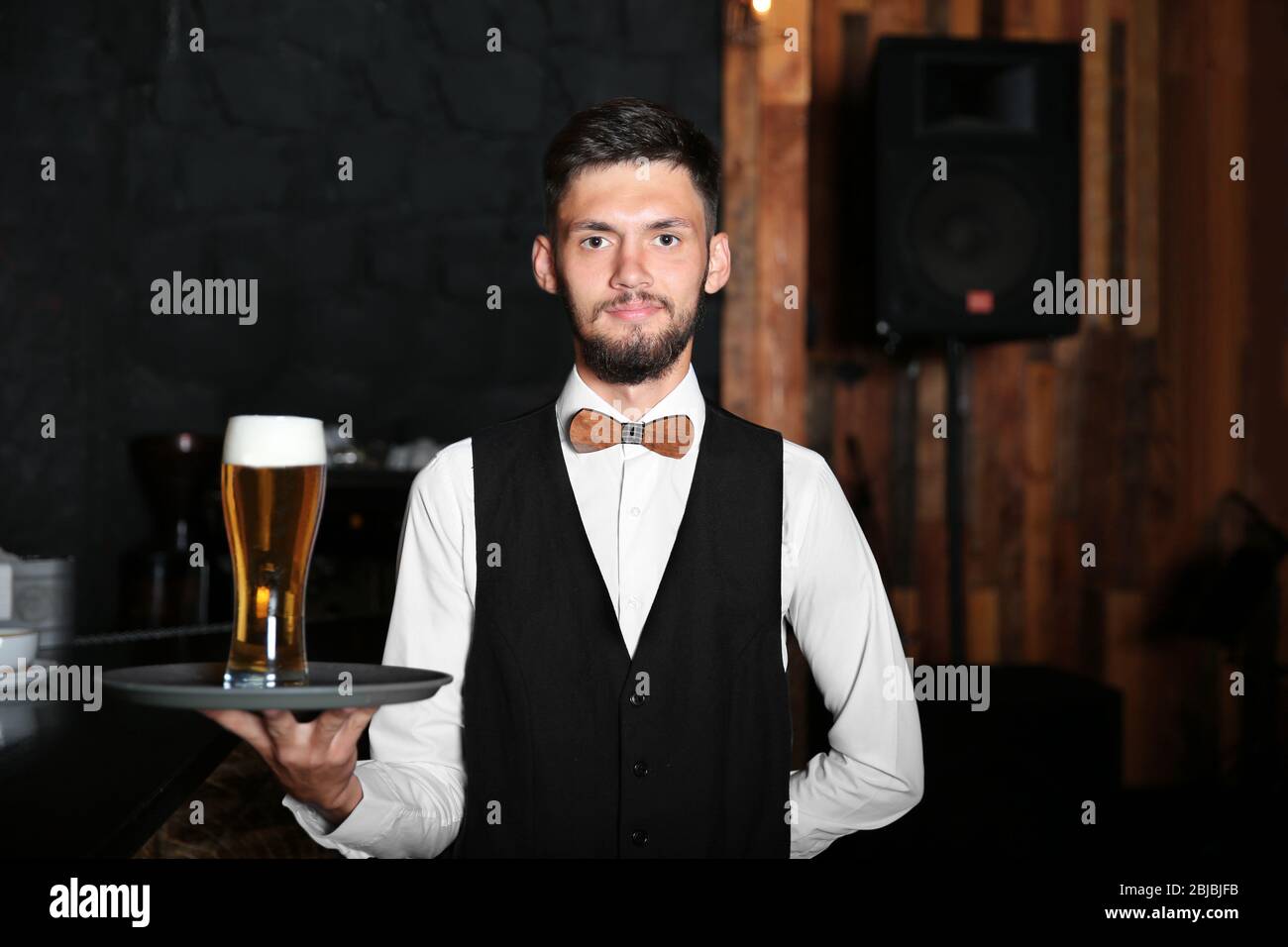 Waiter holding tray with glass of beer near wooden bar counter Stock ...