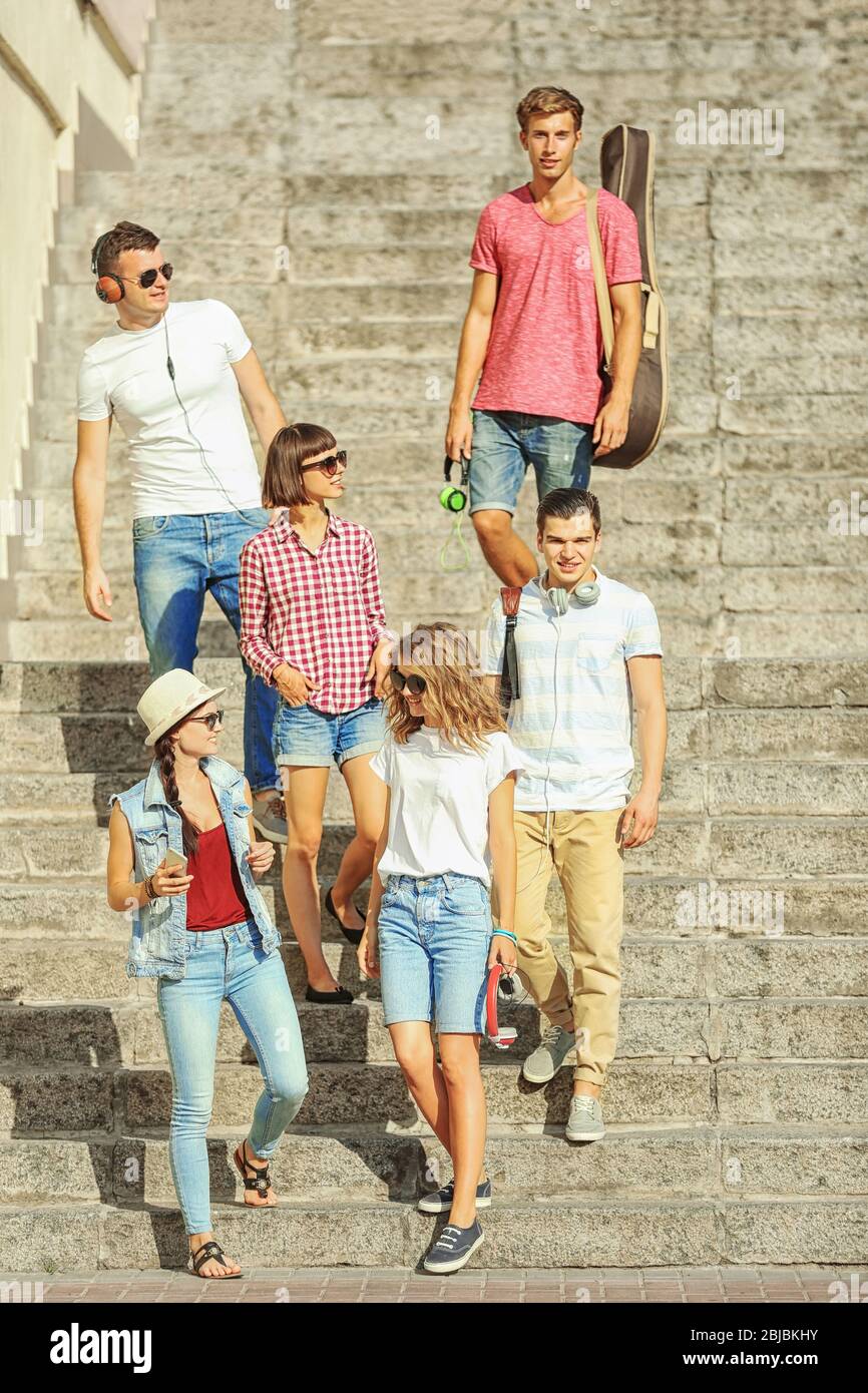 Happy young friends going down on stairs Stock Photo - Alamy