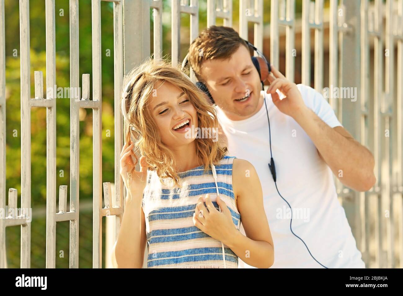 Happy friends listening to music on street Stock Photo - Alamy